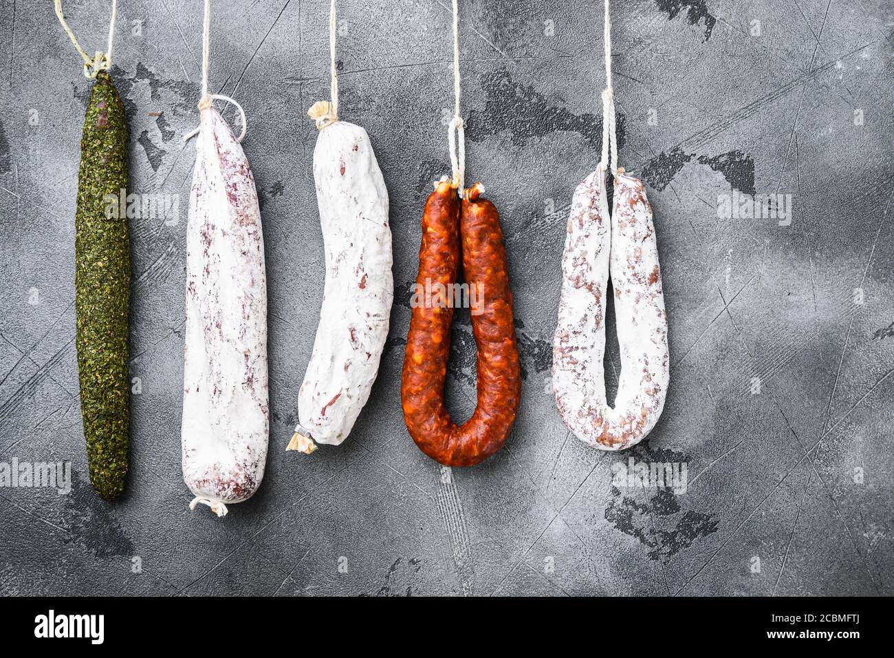 Spanish dry salami from a rack at market on grey textured background ...