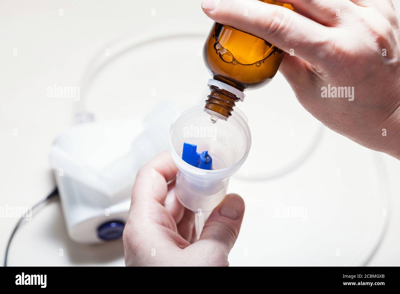 woman dripping inhalation solution from vial into nebulizer close up ...