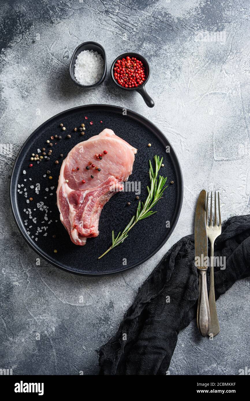 pork meat, cutlet in a black round plate on a grey textured stone ...