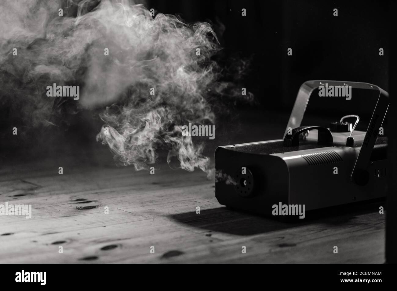 Smoke coming from the smoke machine standing on the floor. Black and ...
