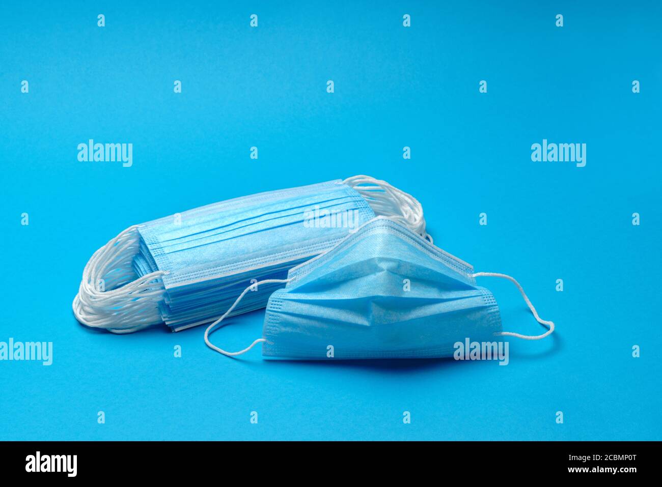 Stack of Disposable blue medical face masks on blue background Stock ...