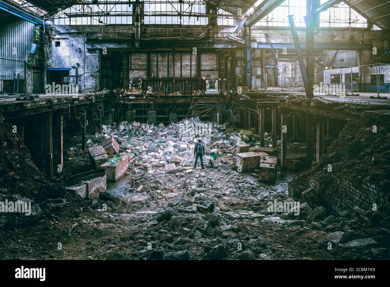 View of a man standing inside an old factory that has been demolished ...