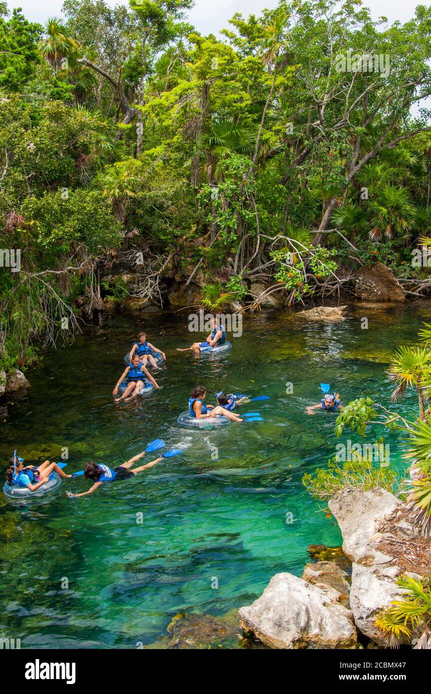 People floating down a small river in inner tubes at the Xel-Ha Park, a ...