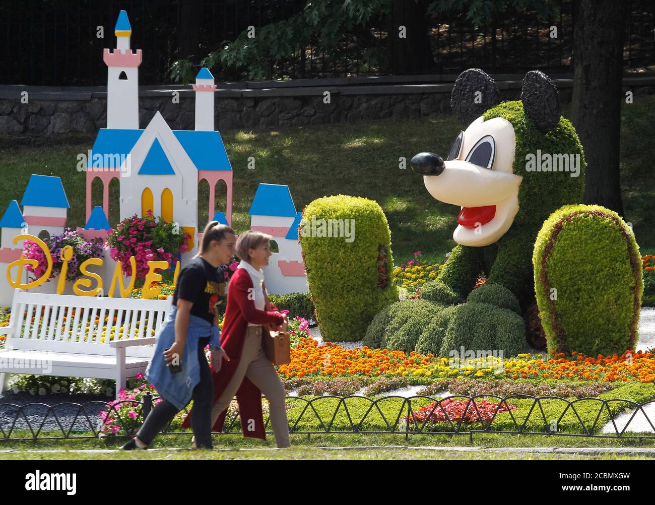 Visitors walk past a Mickey Mouse cartoon character during the ...