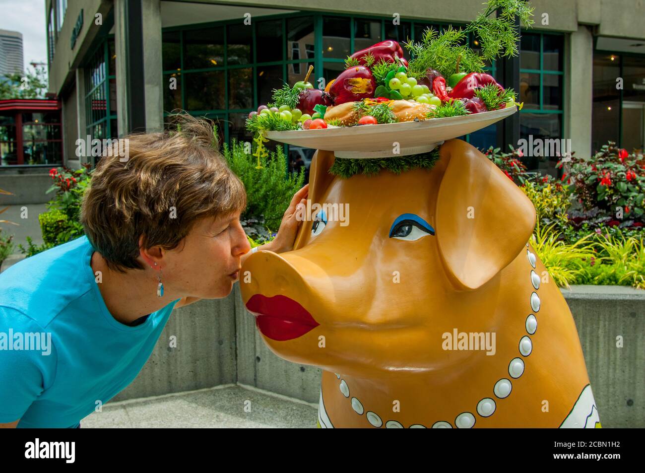 A woman (model released) is kissing a pig statue at the Pike Place ...