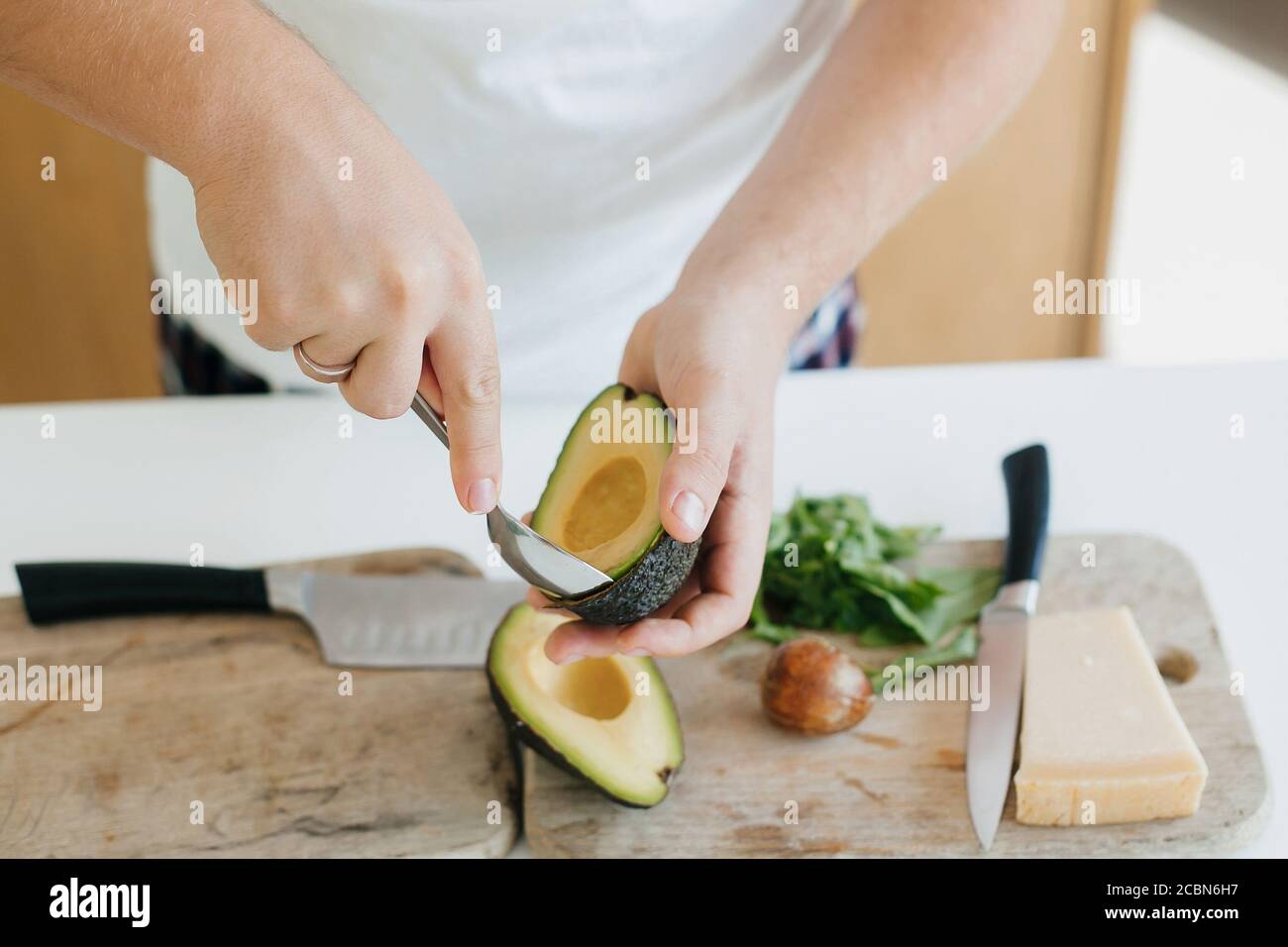 Person peeling perfectly ripe avocado with spoon for sandwich on modern ...