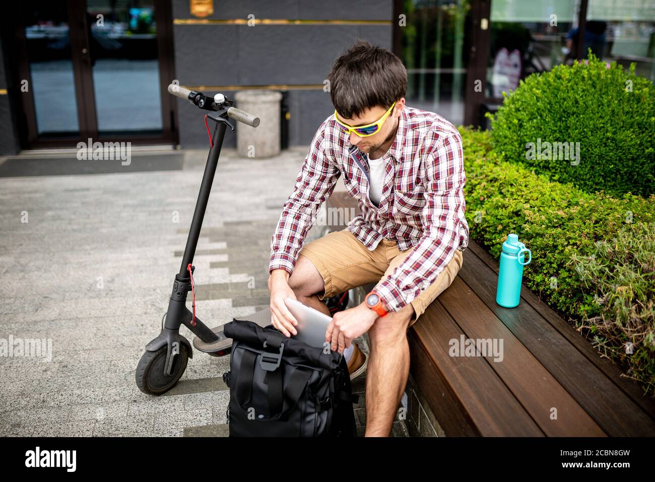 Man Putting Laptop in Backpack outside sitting near electric transport ...