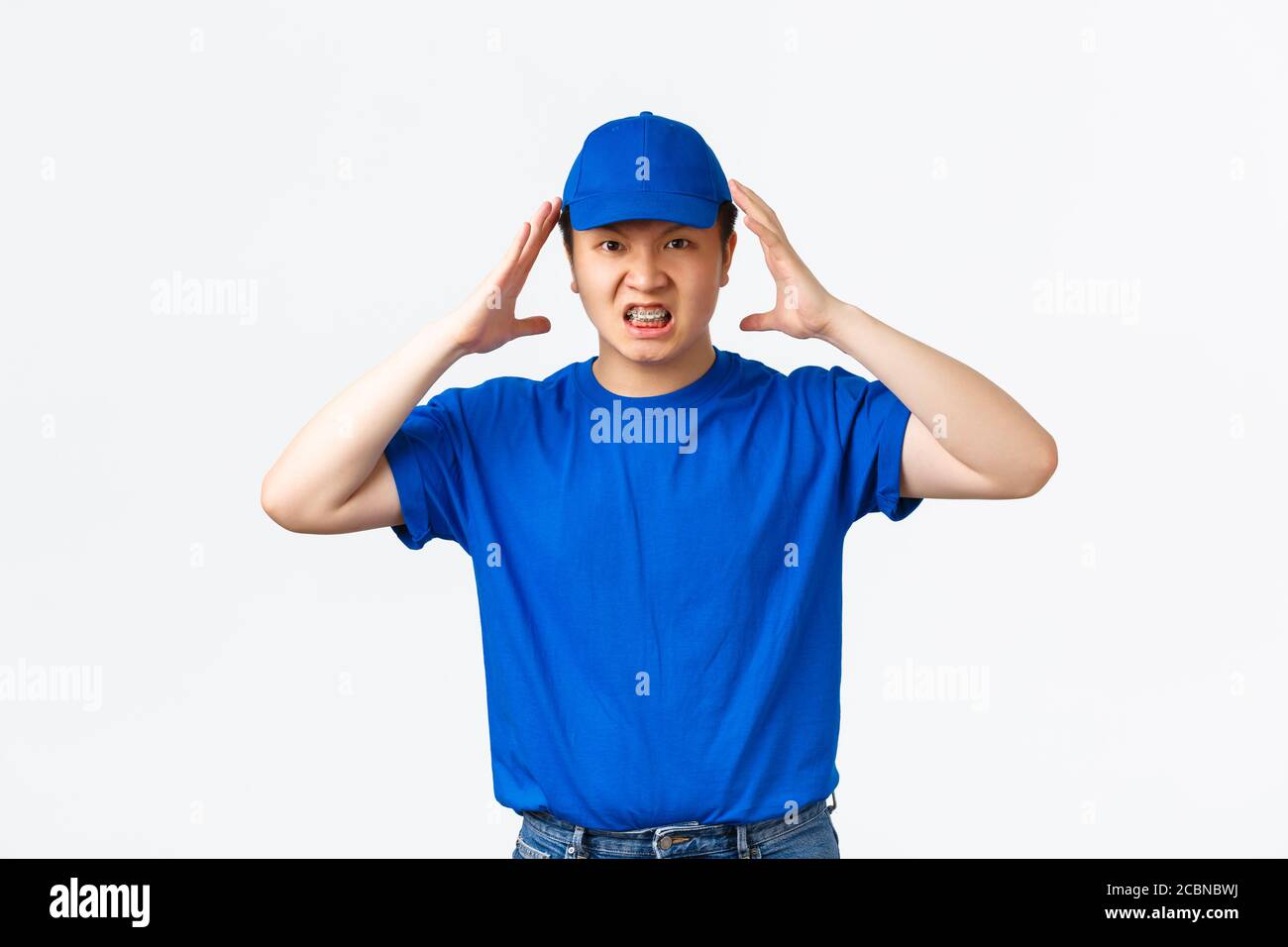 Pissed-off and angry asian delivery man in blue uniform shaking hands ...