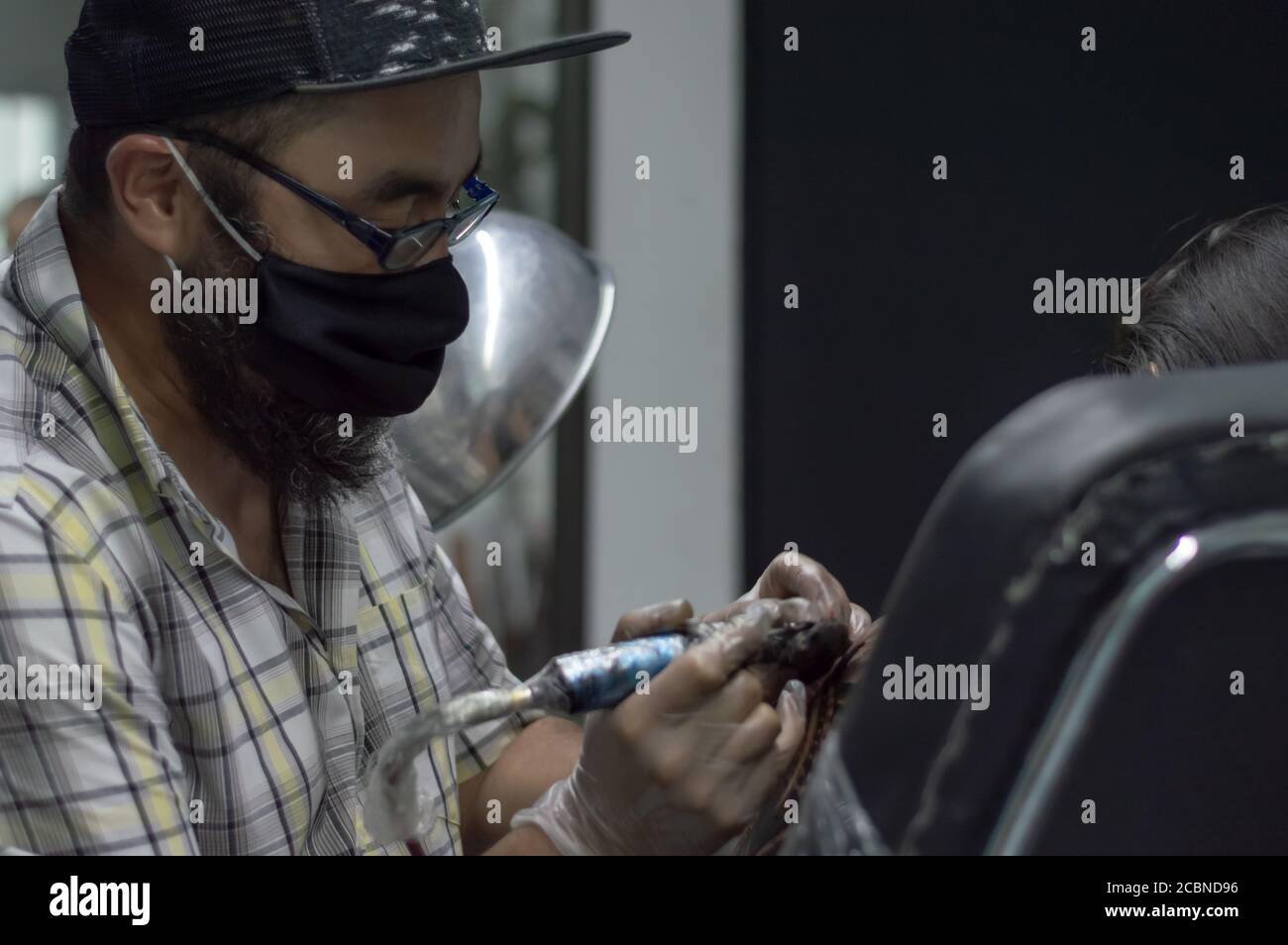 Closeup shot tattoo artist holding a tattoo machine tattooing a person ...
