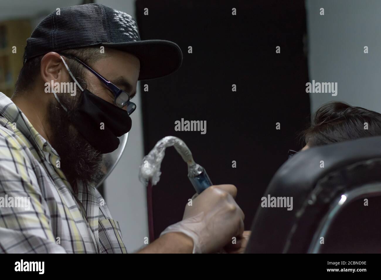 Closeup shot tattoo artist holding a tattoo machine tattooing a person ...