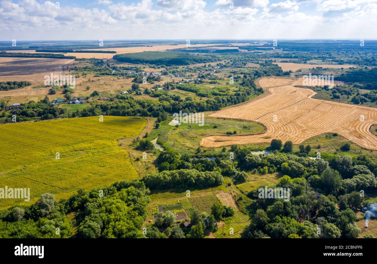 aerial photography of a winding river skirting a mown field and flowing ...