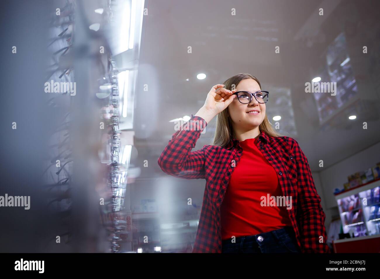 A visually impaired girl chooses glasses. She is wearing a shirt and a ...
