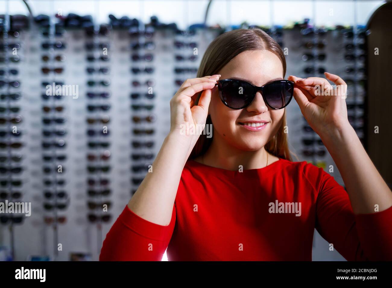 Beautiful young girl chooses sunglasses in an optics store Stock Photo ...