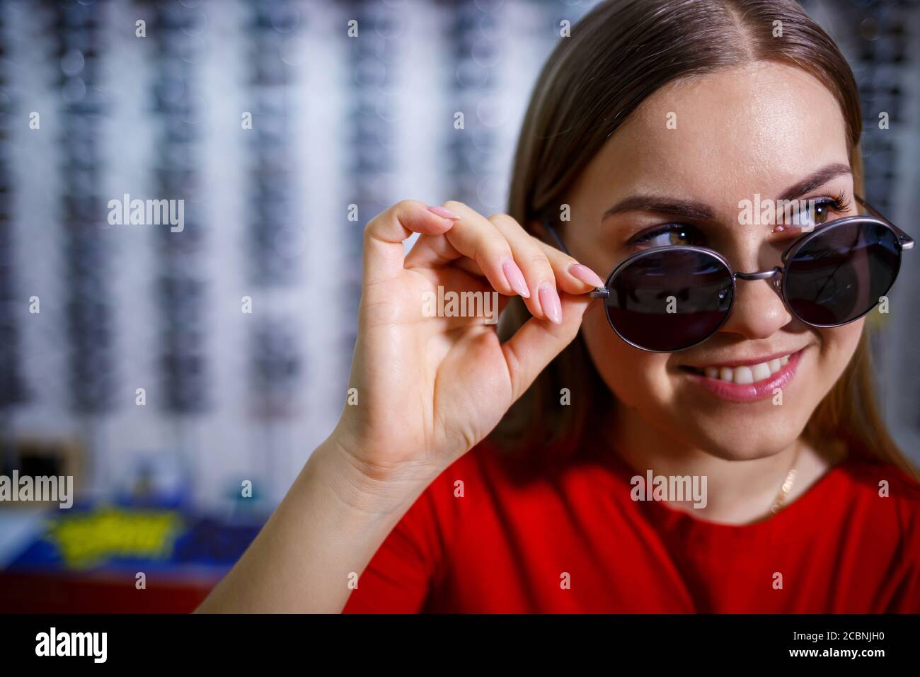 Beautiful young girl chooses sunglasses in an optics store Stock Photo ...