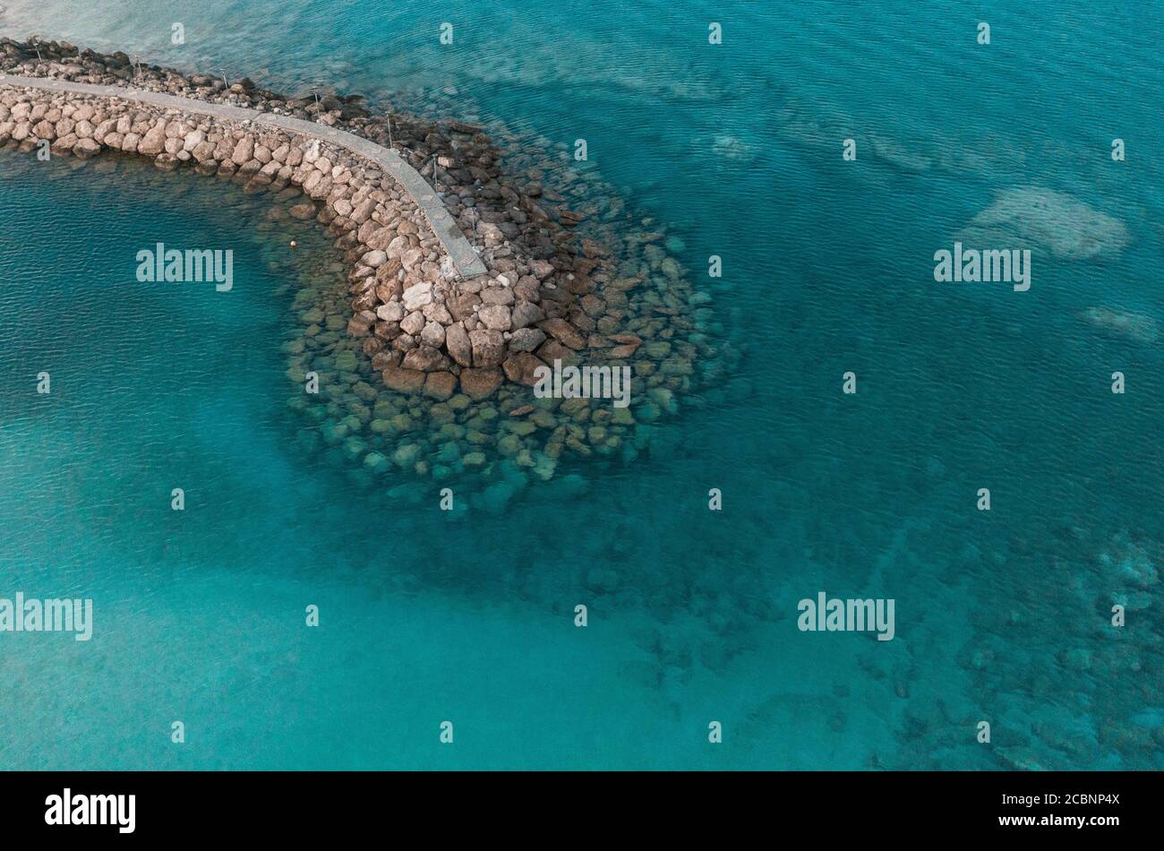 Bird's eye view of a crystal clear sea surrounded by rocks under the ...