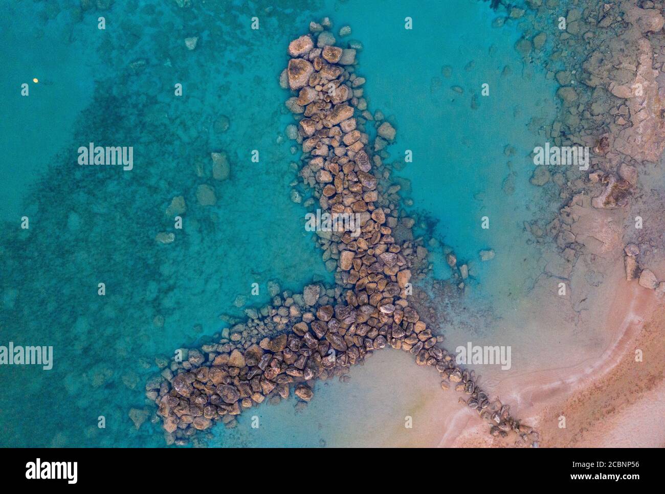 Aerial shot of a crystal clear sea surrounded by rocks under the ...