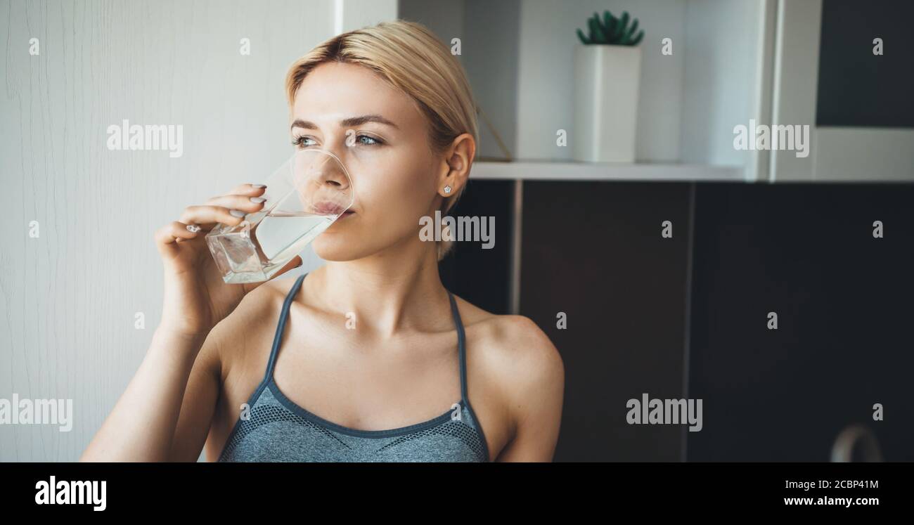 Young fitness lady drinking water after yoga exercises wearing ...