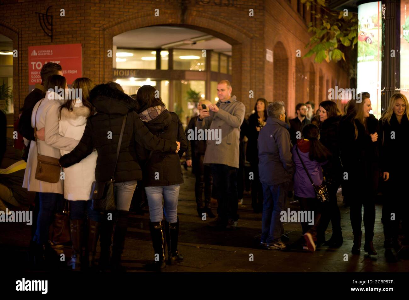 People posed for a group photo in a busy street scene, city and night ...