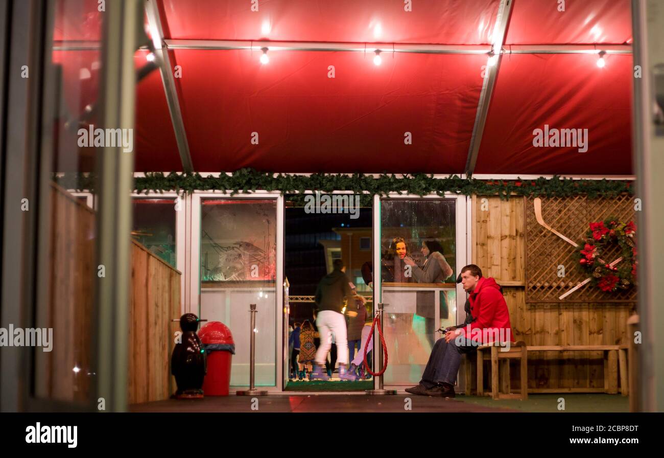 Man waiting in entrance of ice rink, 2 women talking behind the window ...