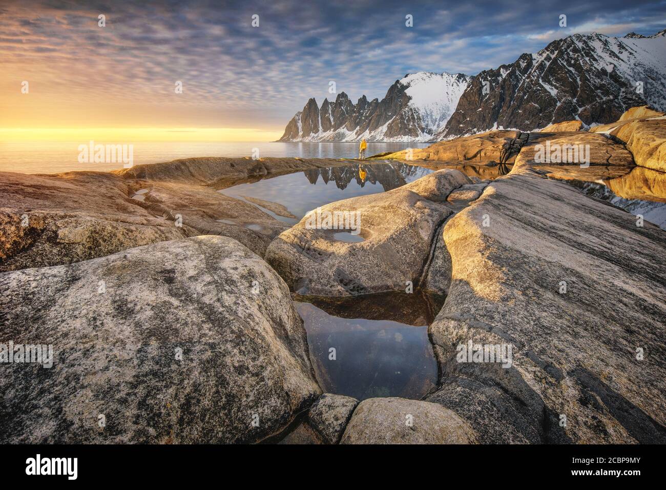 Person with yellow jacket standing on the rocky beach of Tungeneset ...