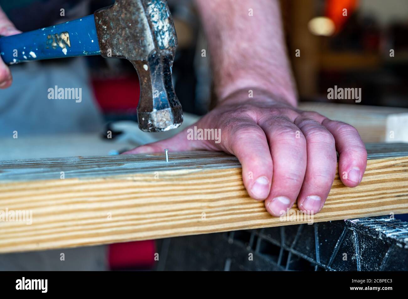 practice of striking a nail head with a hammer to drive it into wood ...