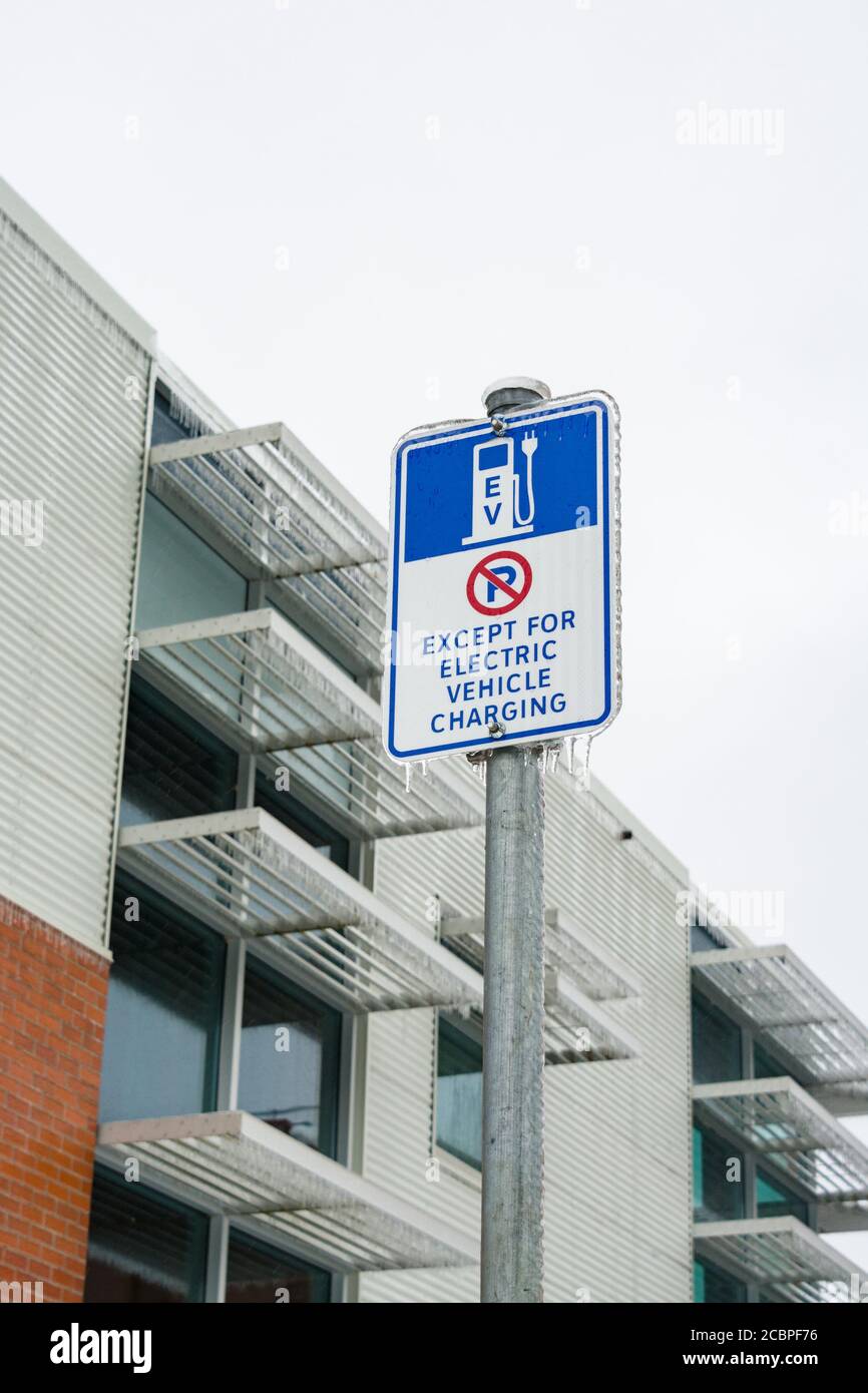 EV charging station sign in icicles with office building on the ...