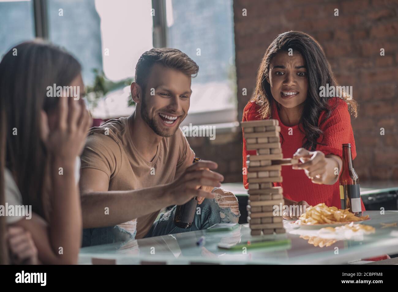 Concentrated friends playing Jenga at the party Stock Photo - Alamy
