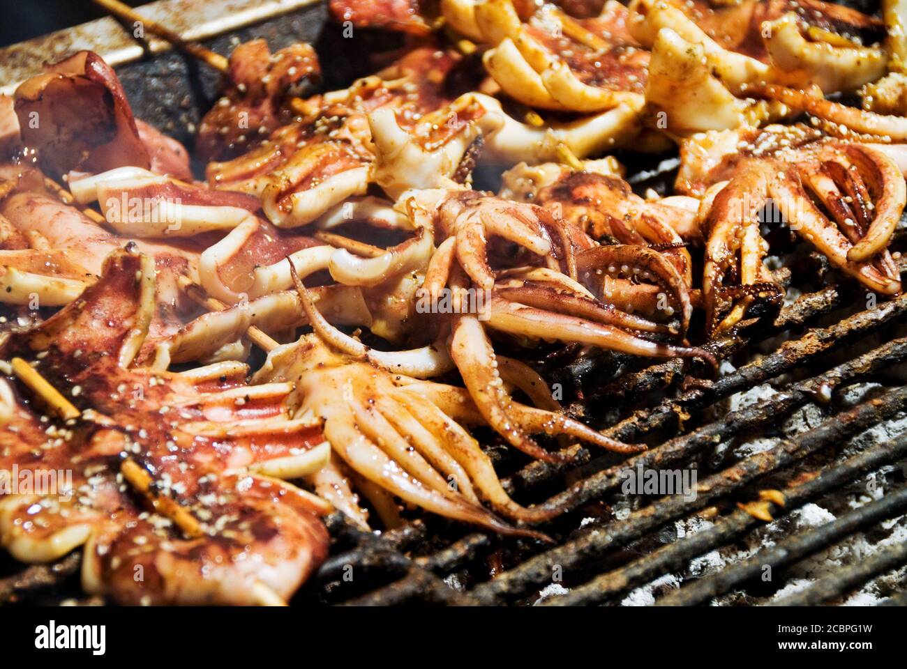 Stack of many grilled squid skewer on the grill in the night market ...