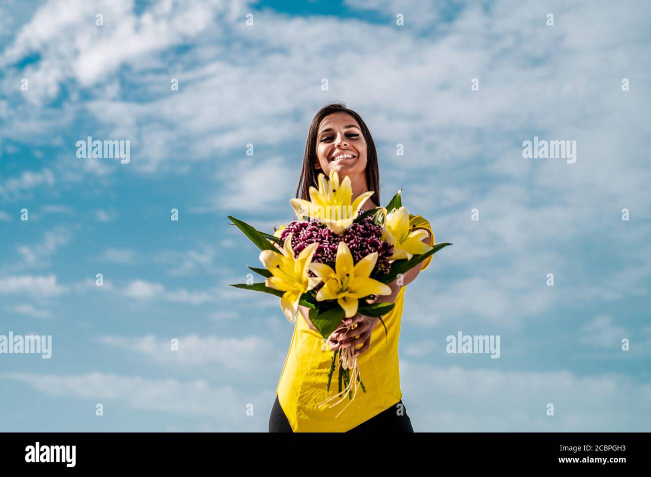 A low angle shallow focus shot of a female holding a bouquet of flowers ...