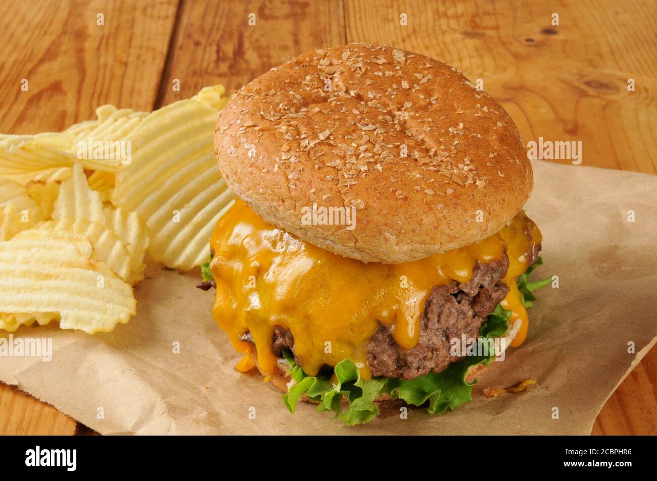 A cheesburger and potato chips on butcher paper Stock Photo - Alamy