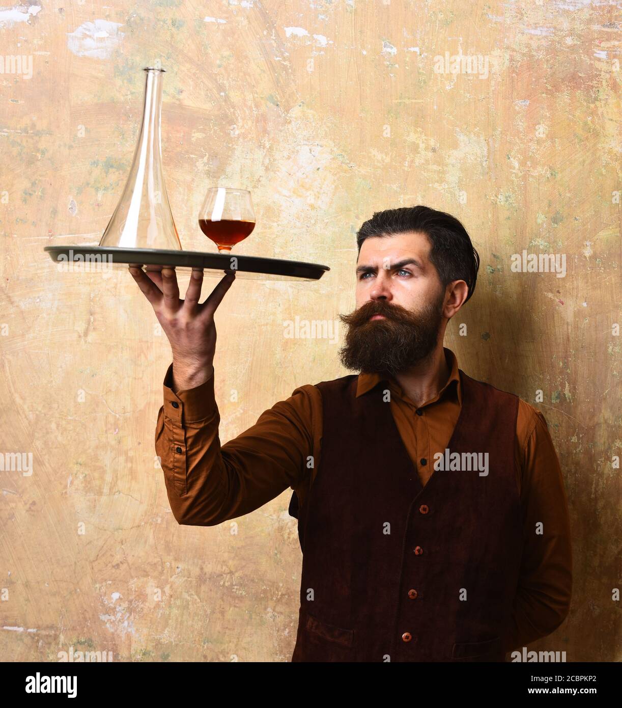 Barman with curious face checks scotch or brandy color. Man with beard ...