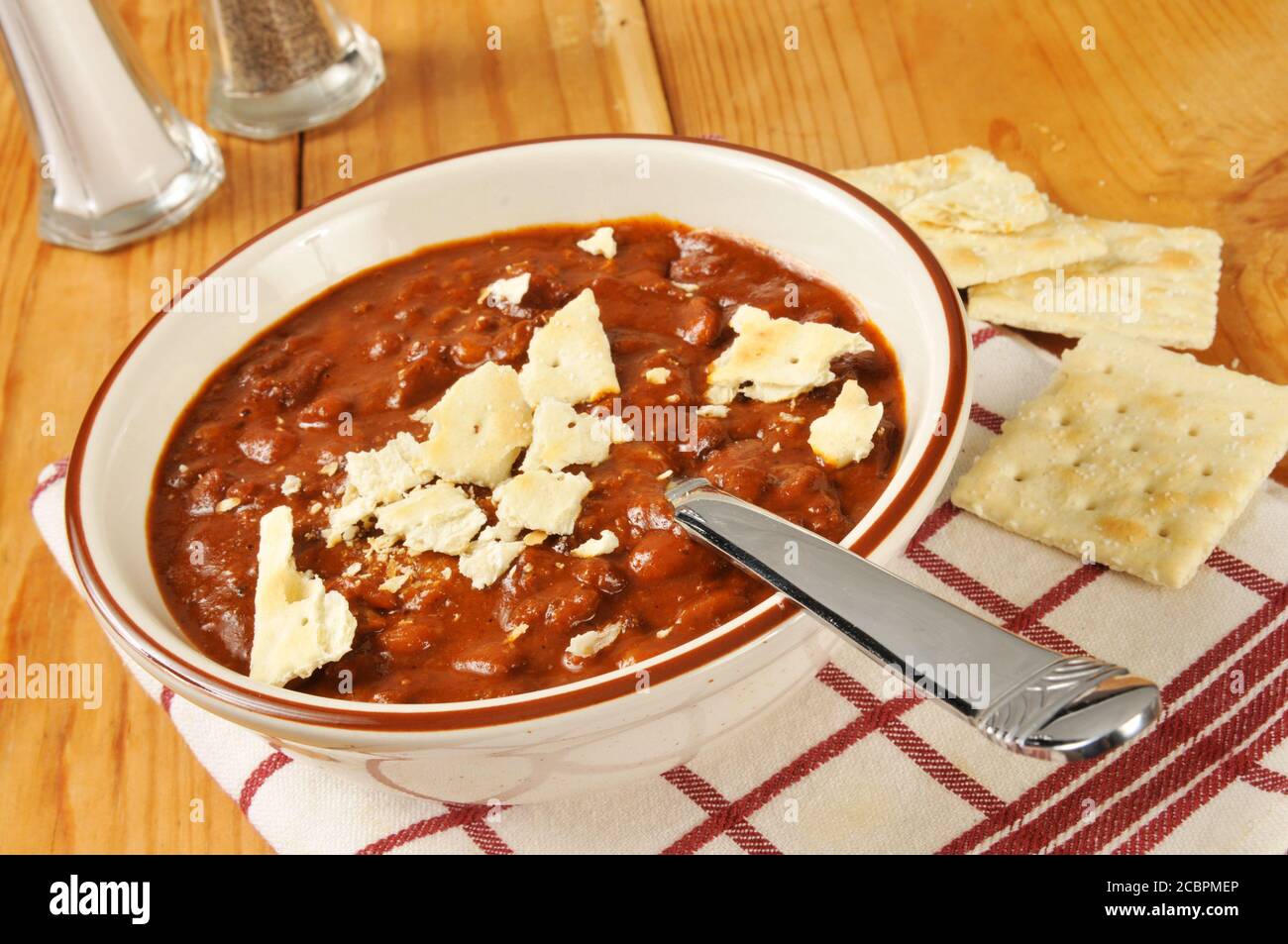 A bowl of chili with saltine crackers on a rustic wood table Stock ...