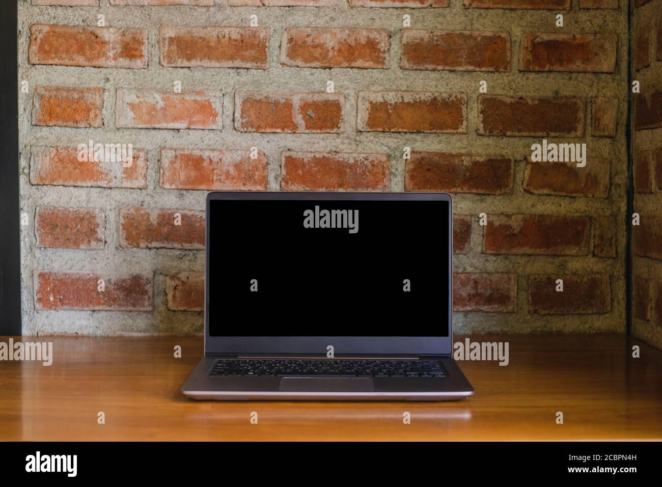 Blank Screen Laptop on the wooden desk and red brick background behind ...