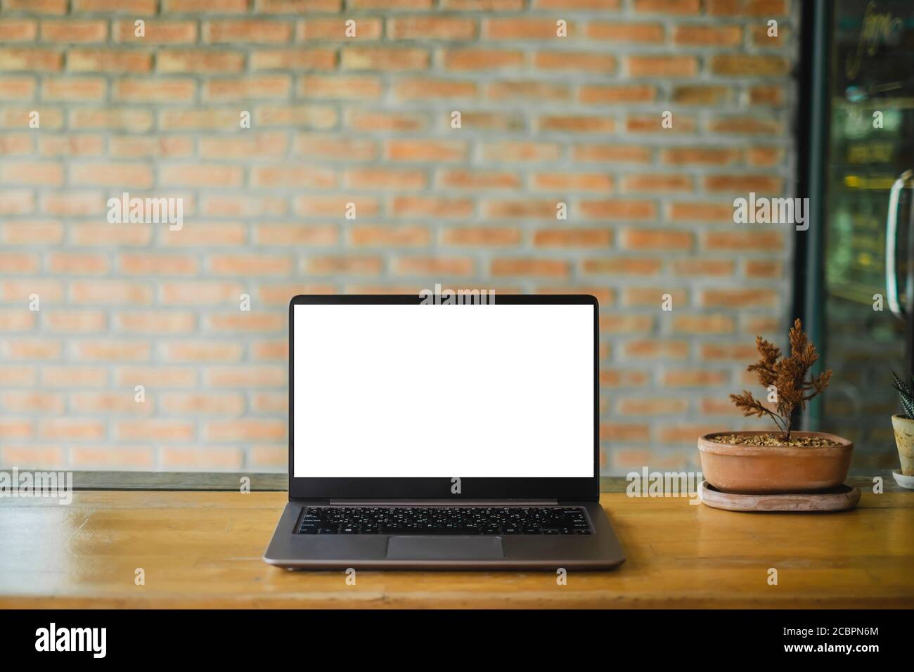 Blank Screen Laptop on the wooden desk and red brick background behind ...