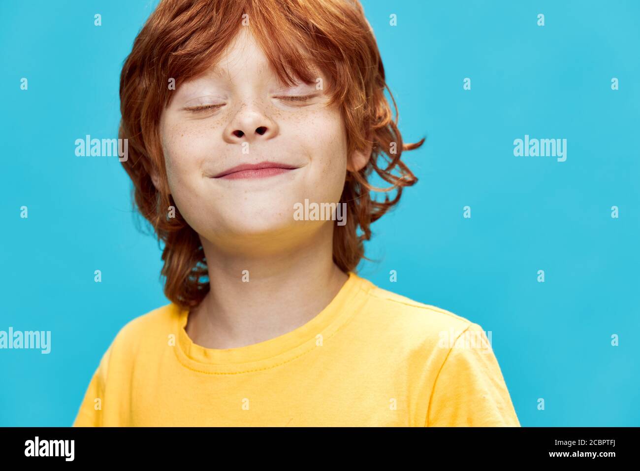 smug red-haired boy in yellow t-shirt on blue background Stock Photo ...