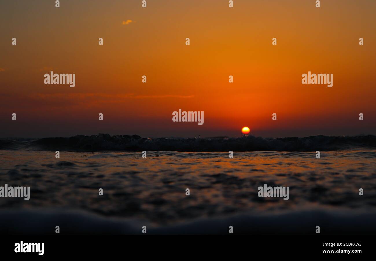 A beautiful lower angle close up view of a sunset on an ocean. With a ...