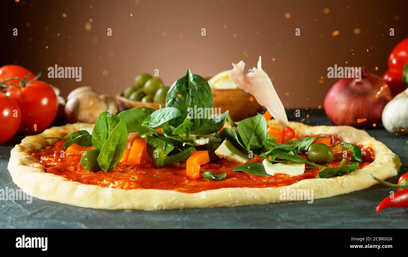 Falling raw ingredients on pizza, freeze motion. Italian traditional ...