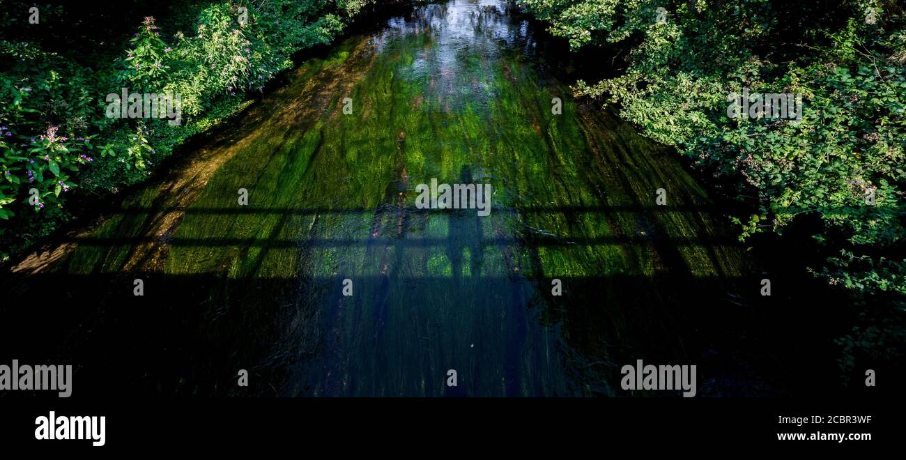 Shadow of a man standing on a bridge over a river Stock Photo - Alamy