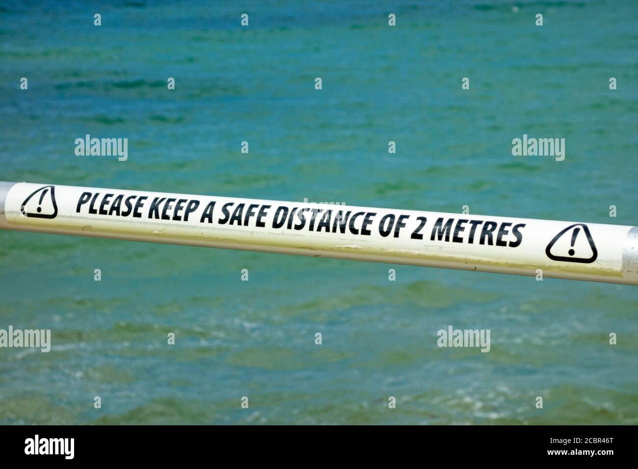 'Please keep a safe distance of 2 metres' sign on promenade railing ...