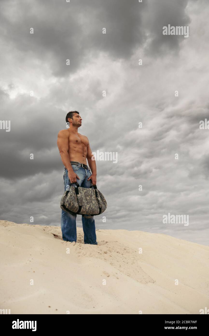 Muscular young man with sand bag in desert. Fitness training workout ...