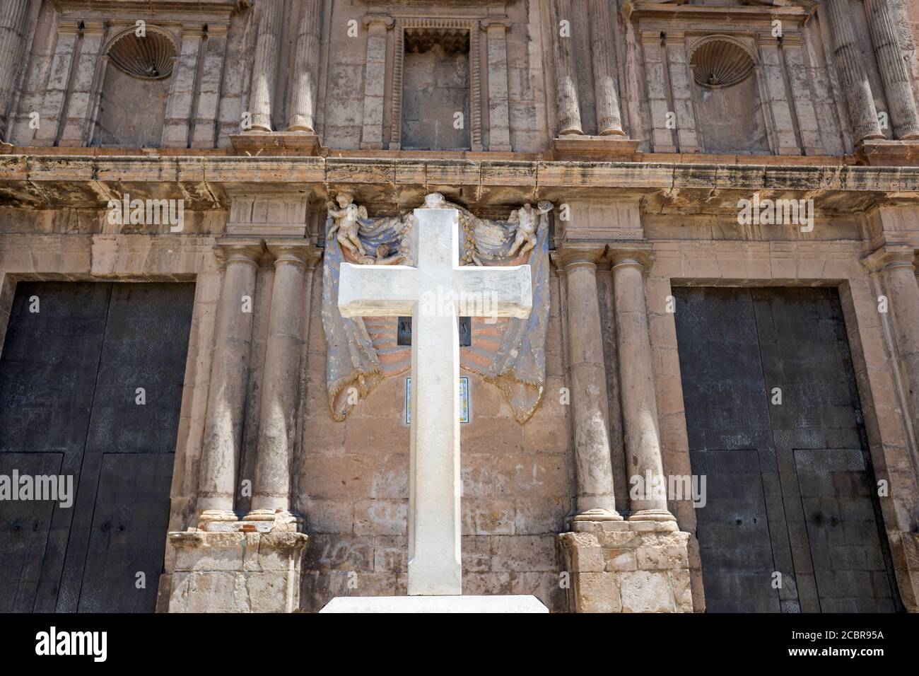 Cross carved in white stone, erected in front of a Christian religious ...