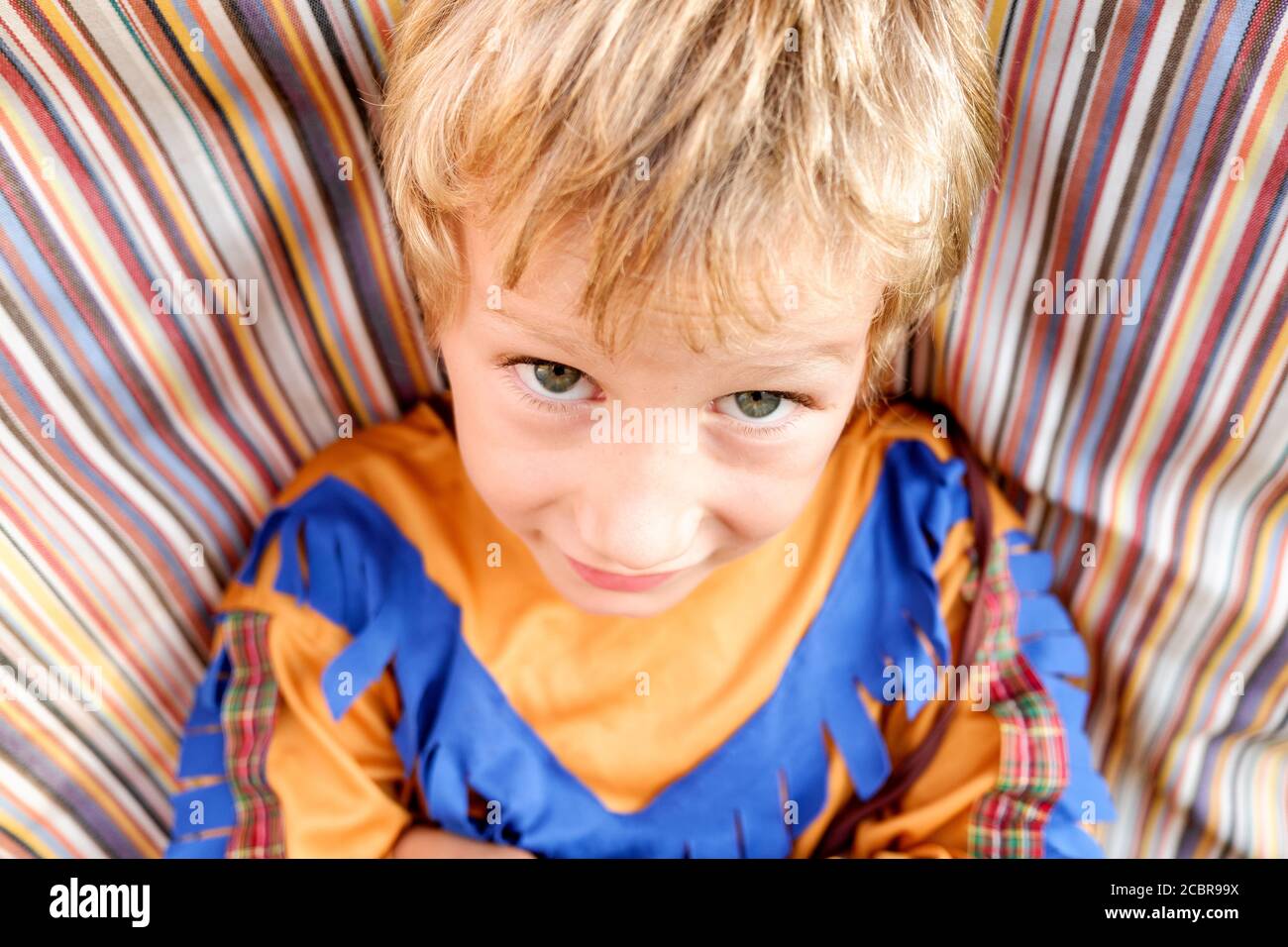 Blond boy seen from above with funny face, dressed up on colorful ...