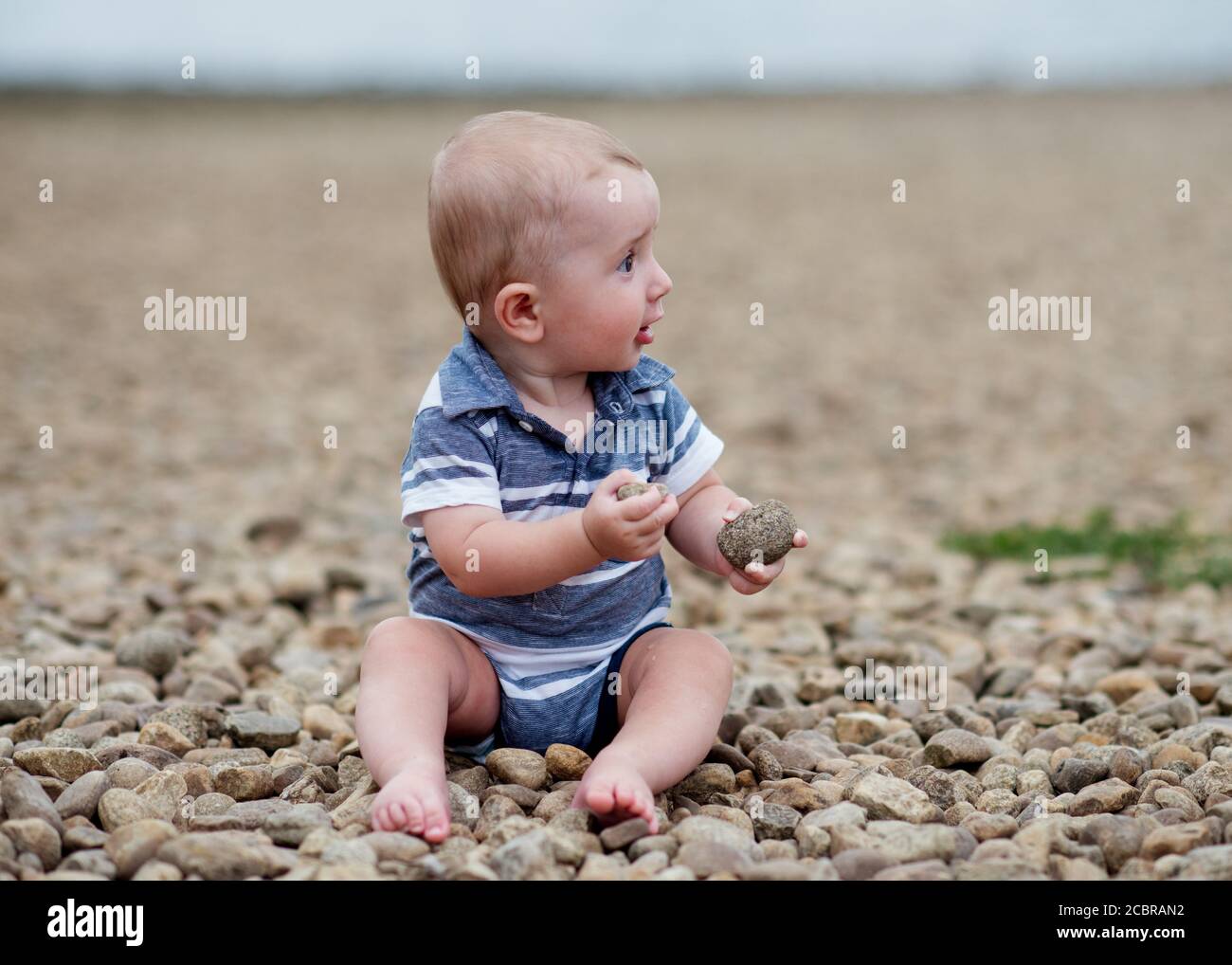 Small boy playng with stones on the seaside Stock Photo - Alamy