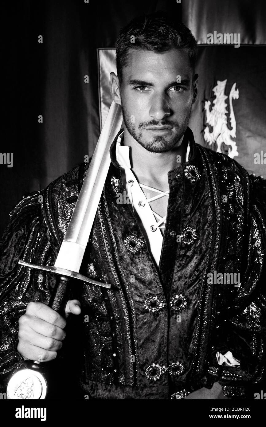 Portrait of attractive king with beard dressed in costume holding a ...