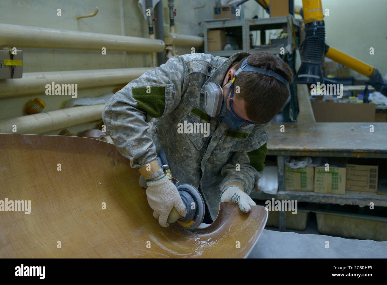 Plane assembly shop. Worker fitting part of fuselage of a light plane ...