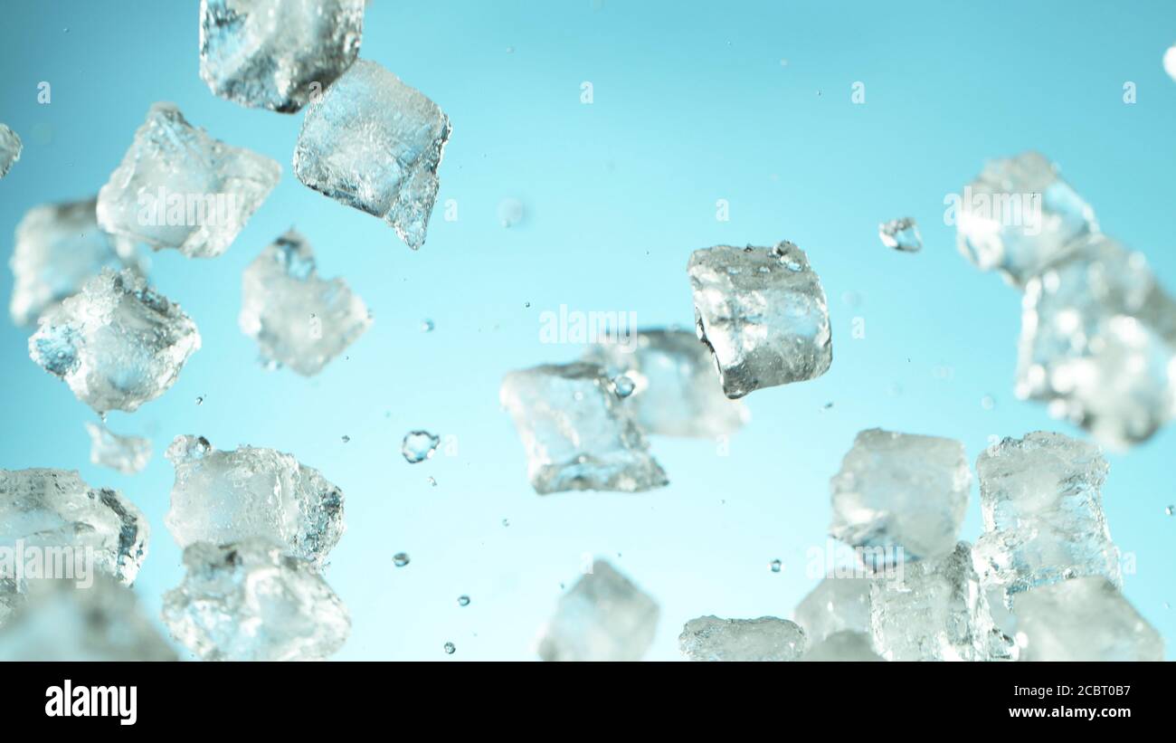 Crushed ice explosion on blue background. Freeze motion of flying ...