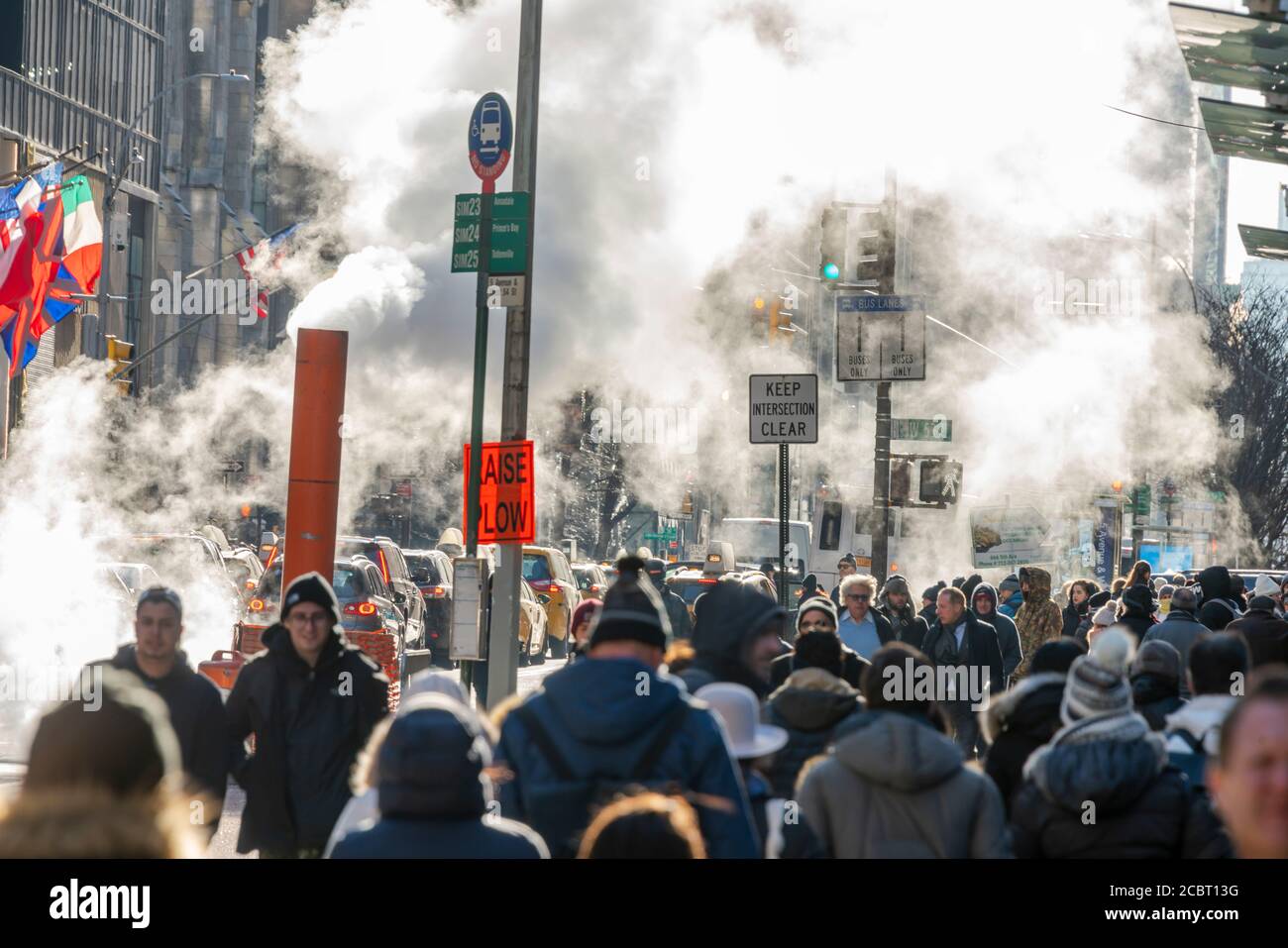 A crowd of people walks down the Midtown Fifth Avenue under the ...
