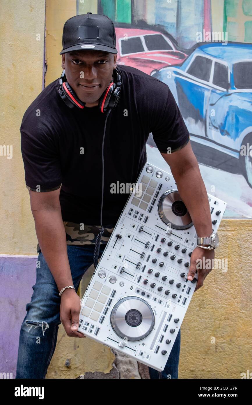 Cuban disc jockey with a modern dj turntable mixer equipment in front ...