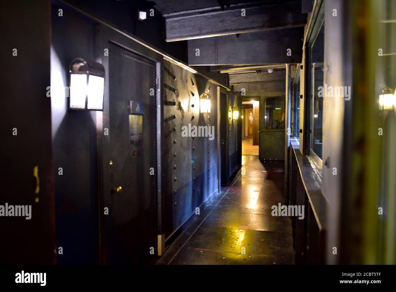 Long dark passageway with doors and light at the end Stock Photo - Alamy