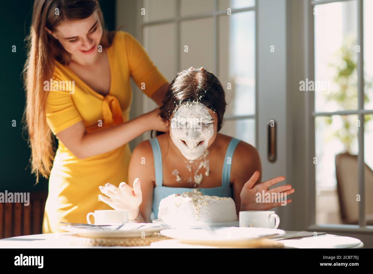 Young woman dips face in white cake with cream. Happy birthday concept ...